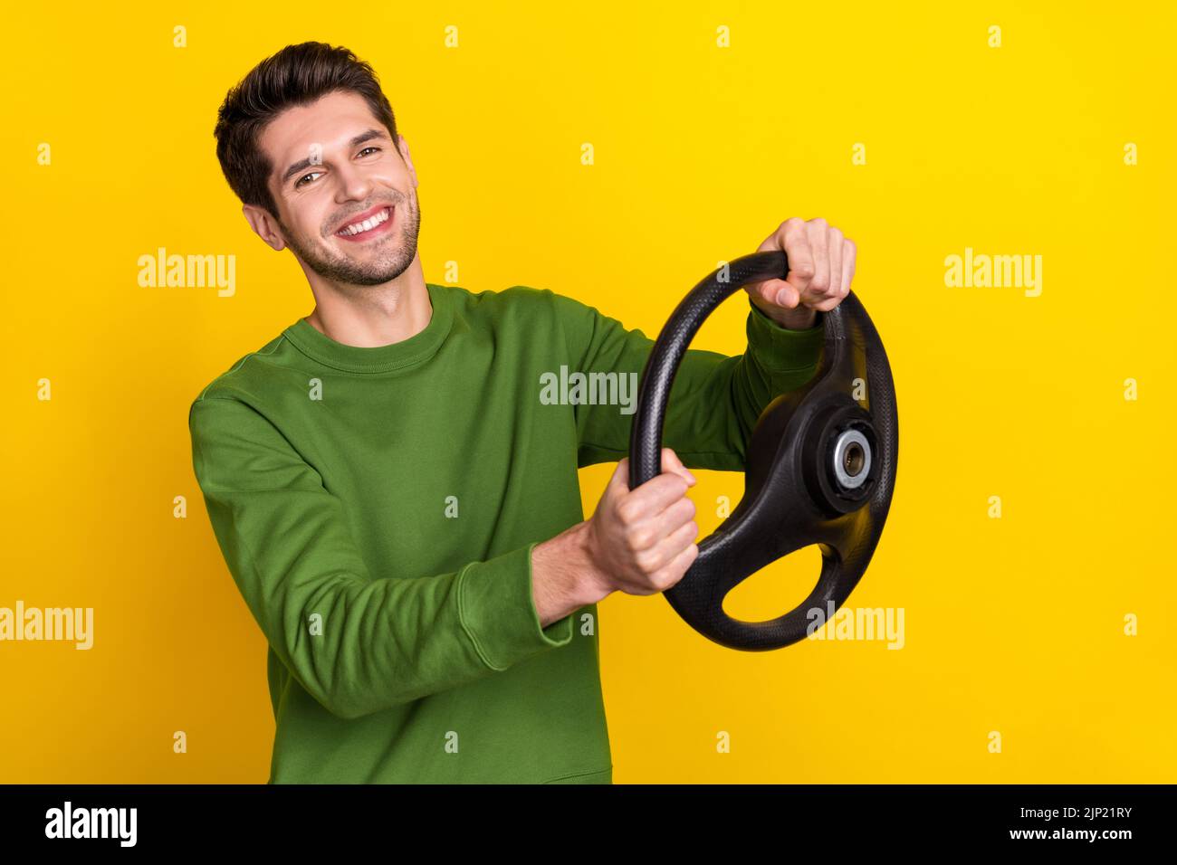 Portrait of attractive cheerful guy holding steering wheel riding ...