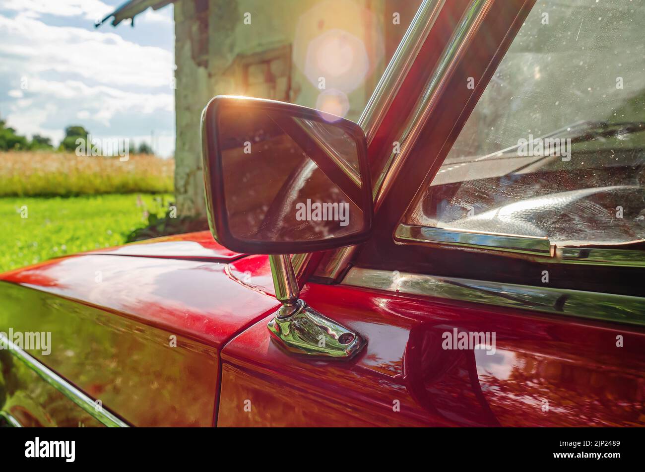 Side mirror of old red Lada car. Sun is reflected in mirror of car ...