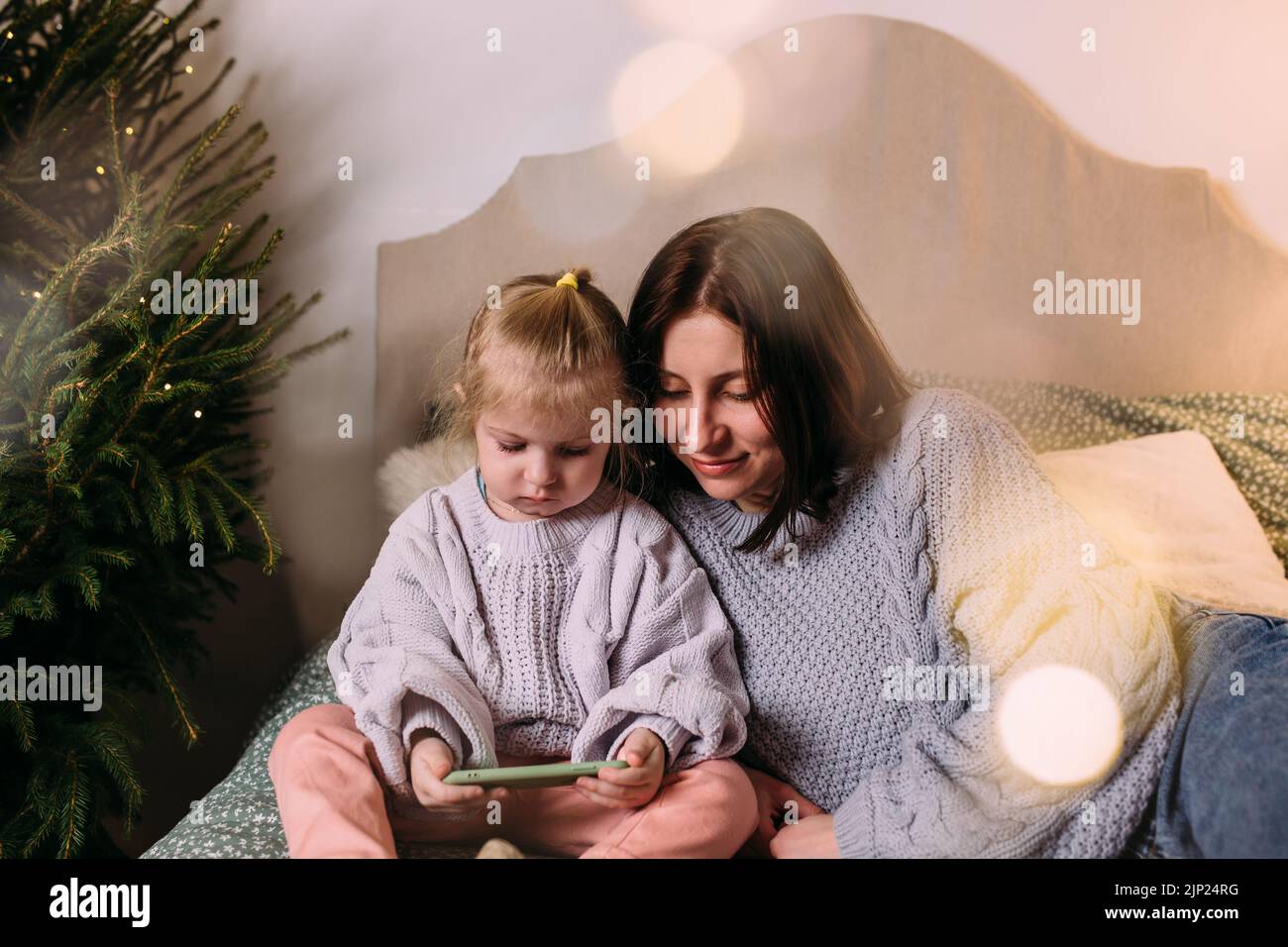 Mom and daughter look at the smartphone at christmas together Stock Photo - Alamy