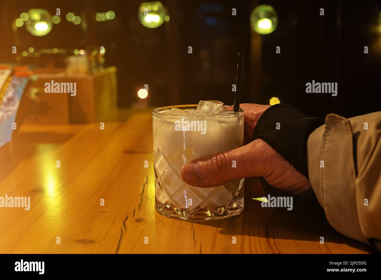 Glass with an alcoholic cocktail in a man's hand Stock Photo - Alamy