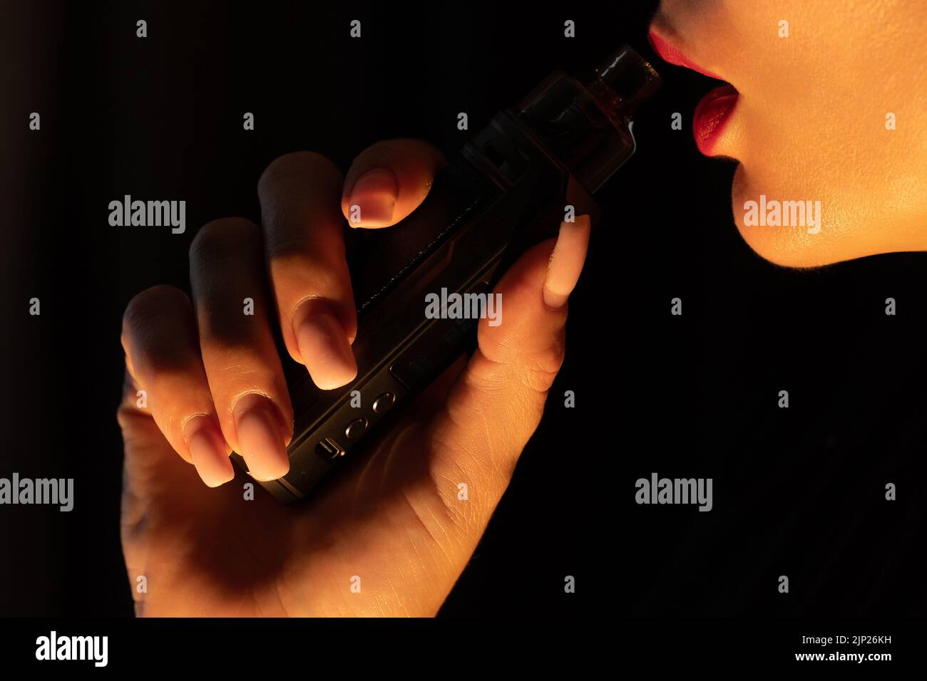 A girl smokes an electronic cigarette and exhales smoke, her lips are ...