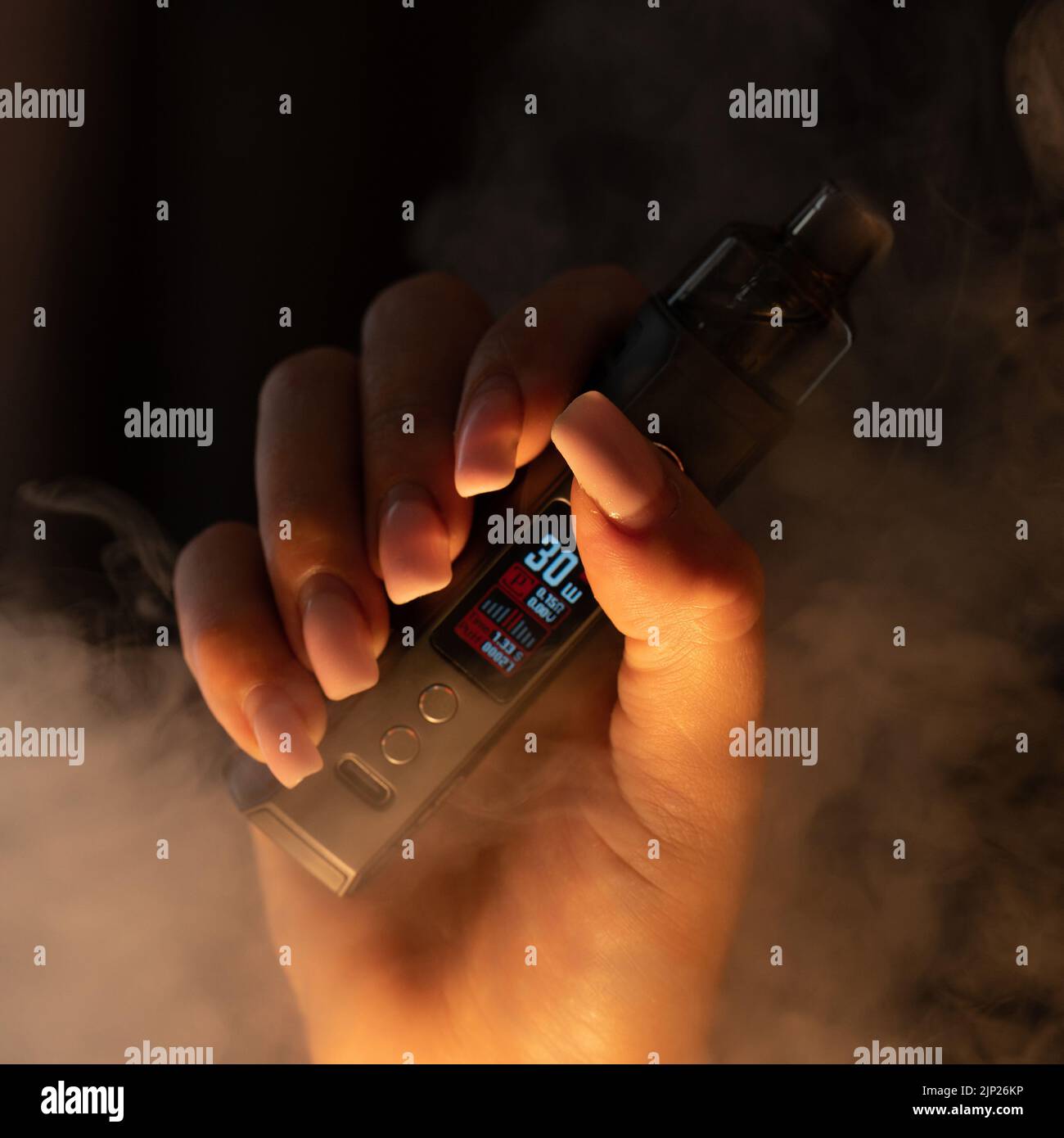 A girl smokes an electronic cigarette and exhales smoke, her lips are ...