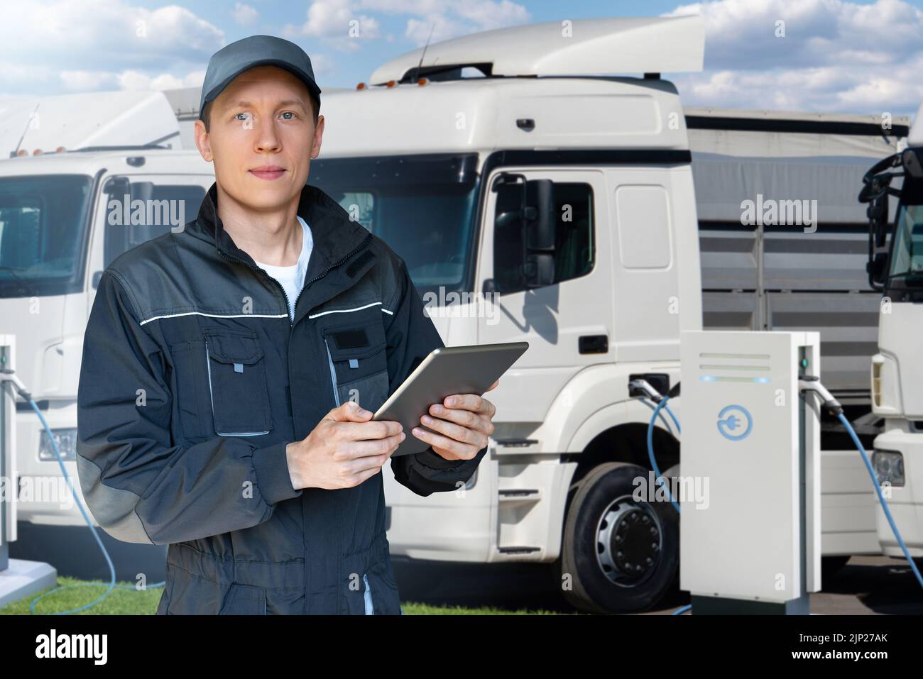 Fleet manager with a digital tablet stands next to electric trucks at ...