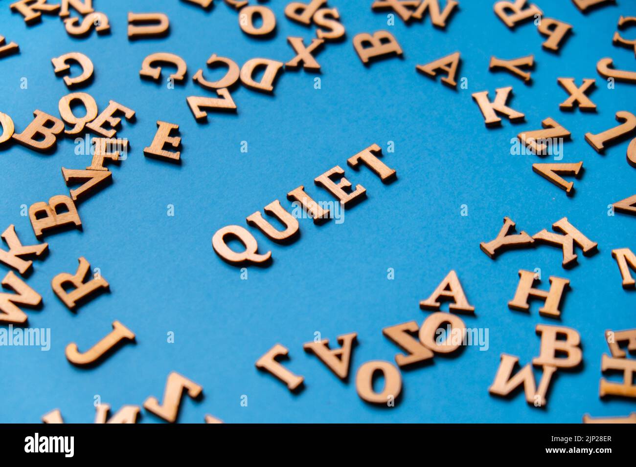 Word QUIET made out of wooden letters on bright blue background ...