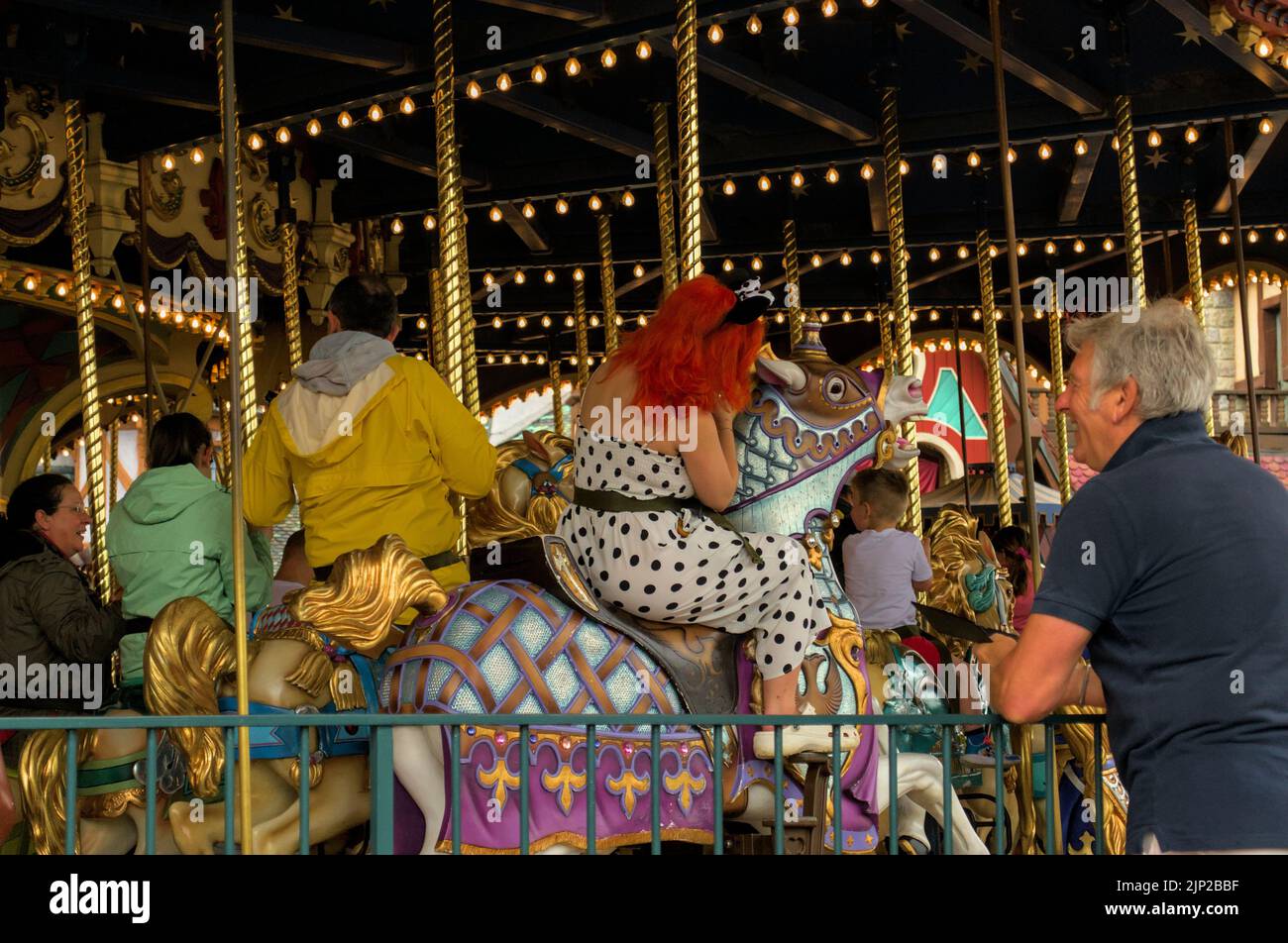 A closeup shot of people on a vintage carousel ride in Disneyland Paris ...