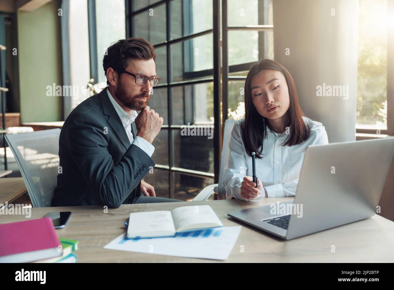 Two focused business people working in a modern office and discussing a ...