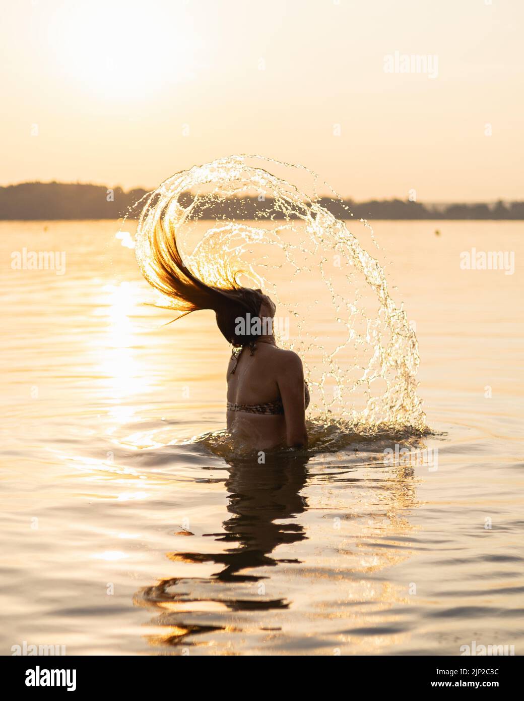 A female swimming in the sea with her hair in the air on the sunset ...