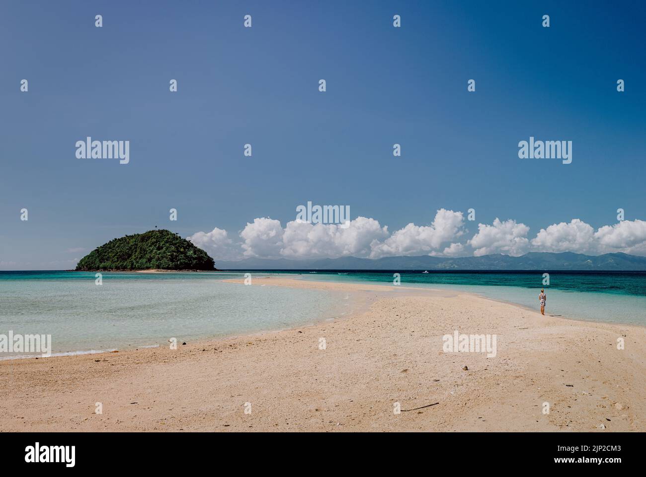 A mesmerizing view of the sandy Bon Bon Beach and a cliff with dense ...