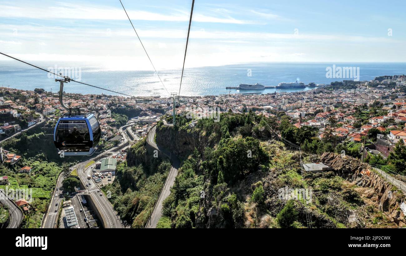 A panoramic view of a city and ocean from a teleferic cabin in Funchal ...