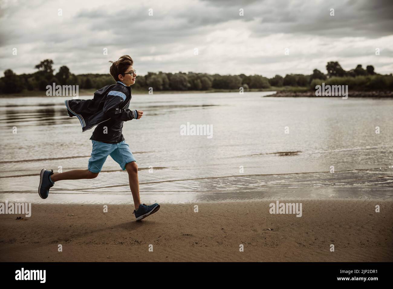 A young teen boy running on coastline of mud flat and enjoy freedom of ...