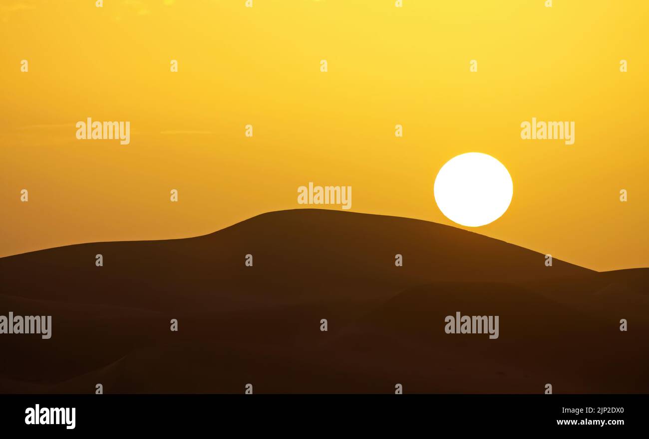 Gold yellow sunset with circular full round sun ball over silhouette of ...