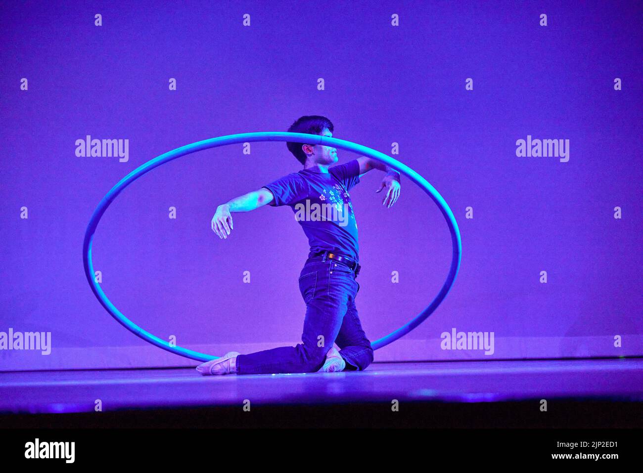 A contemporary ballet dancer kneeled in the middle of a hoop on a stage ...