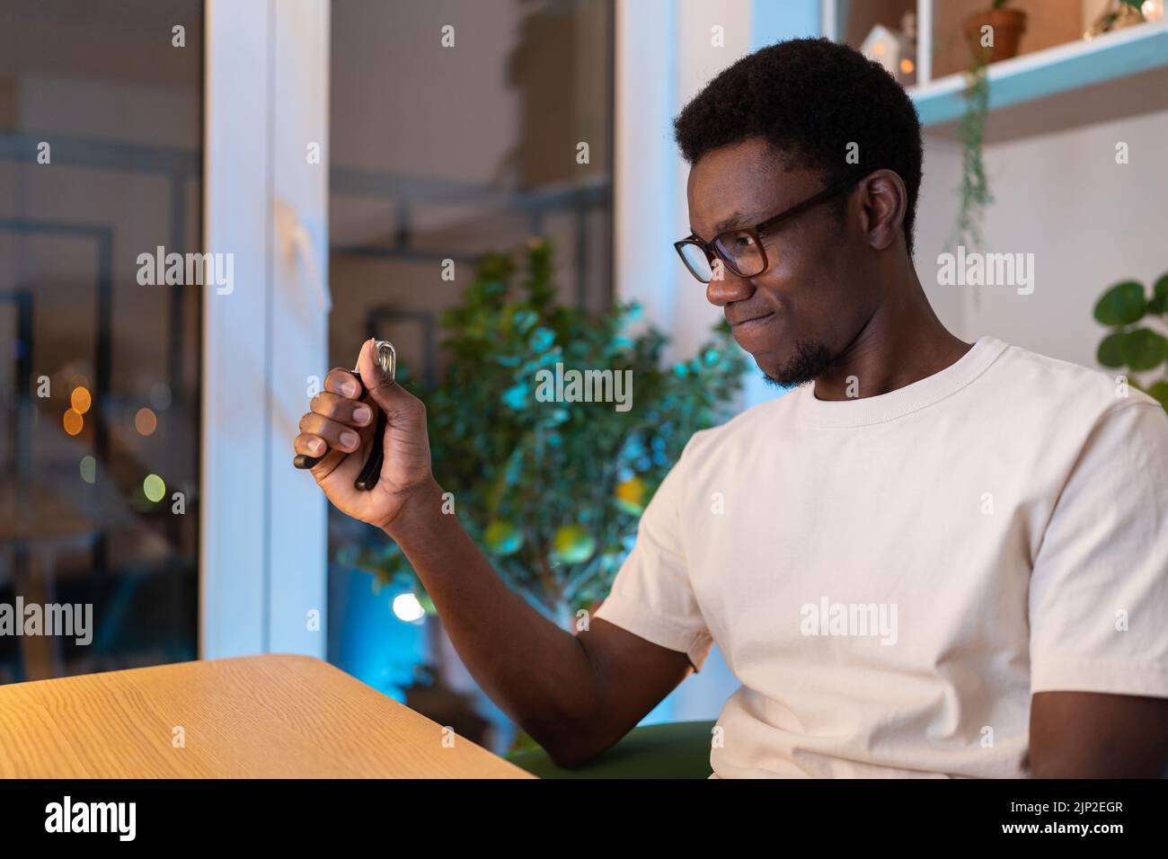 Young African American man takes care of hand wrist using expander ...