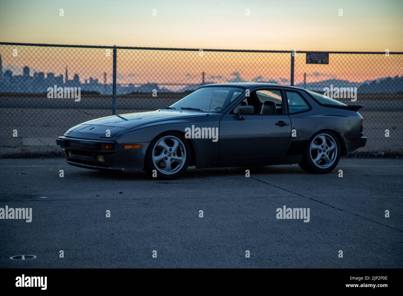 A black Porsche 944 parked in the bay area at sunset in Alameda ...