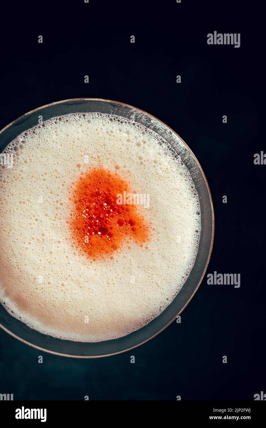 A vertical top view of a foamy cocktail with a red spot Stock Photo - Alamy