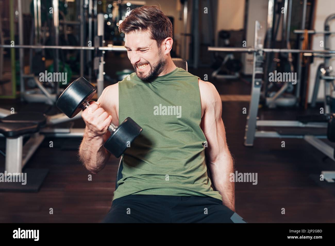 A young attractive man lifting heavy dumbbells at a gym Stock Photo - Alamy