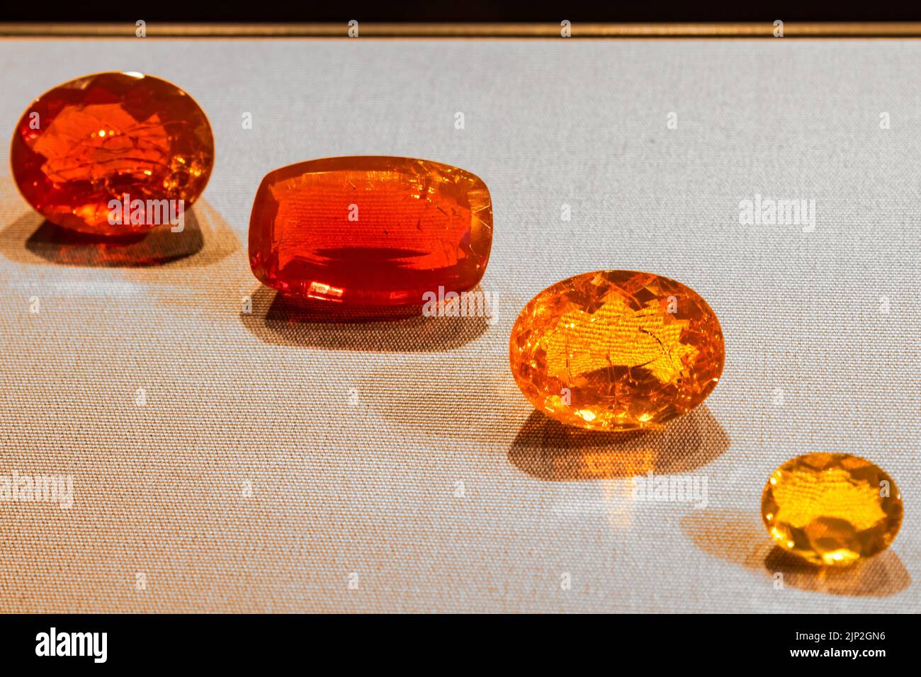 A row of shiny, bright amber gemstones in various shapes and sizes on ...