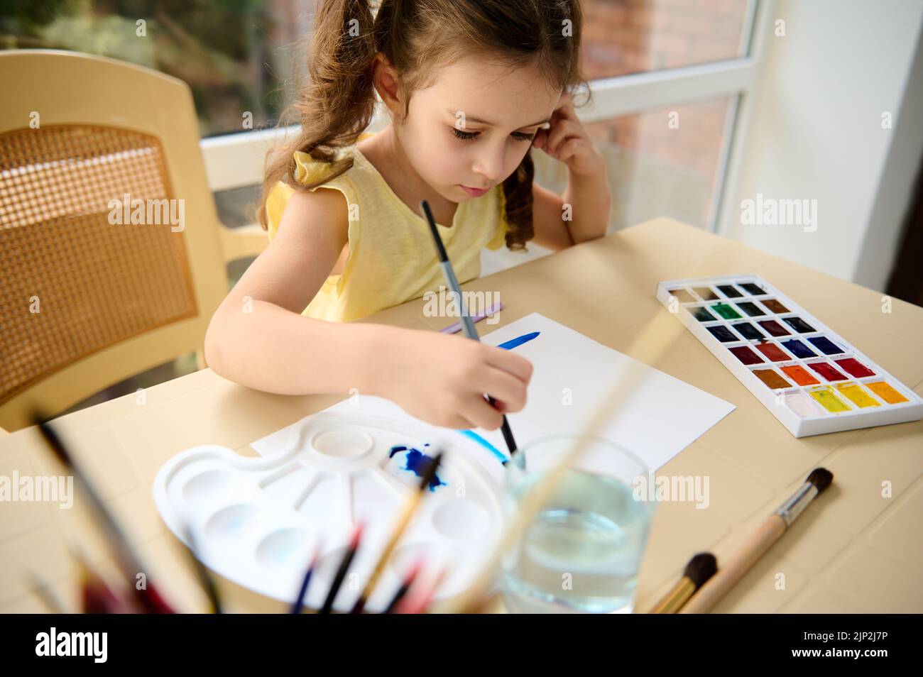 Caucasian schoolgirl, young creative gifted little artist drawing with ...