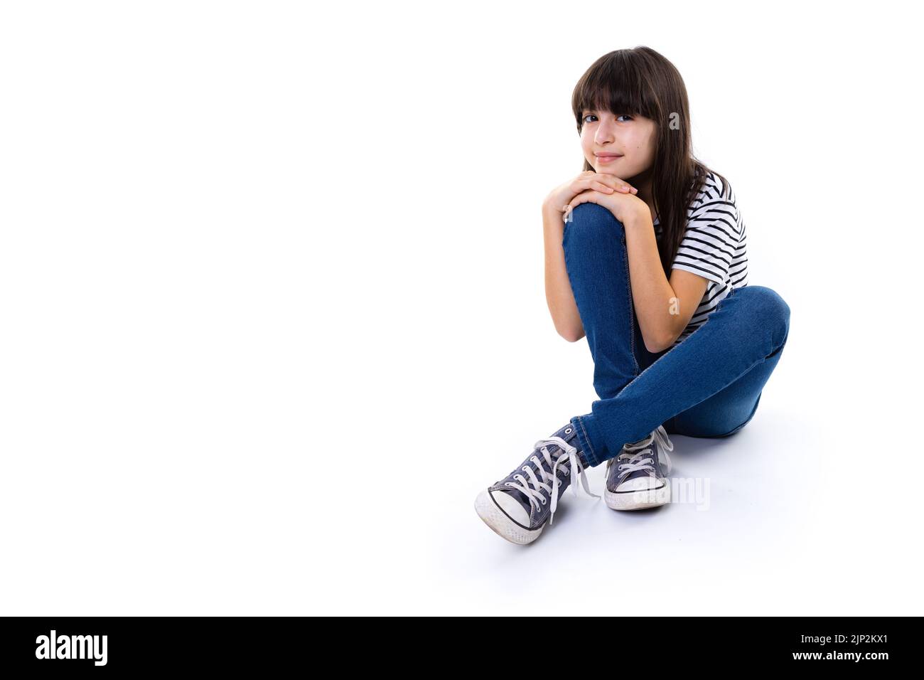 A young 10 year old girl sit on floor rest with hands on knee and smile ...