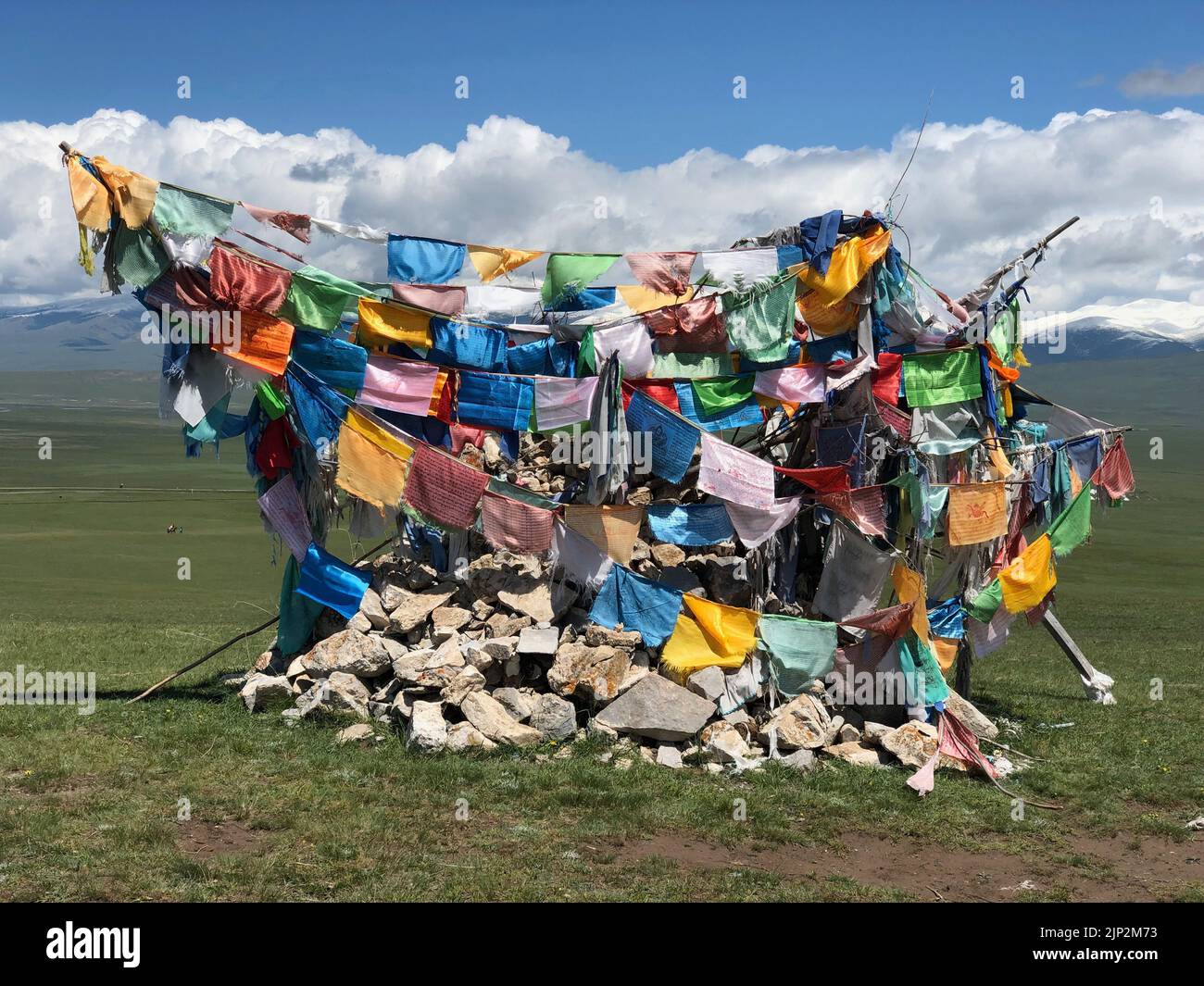 A closeup shot of colorful prayer flags over a pile of stones and rocks ...