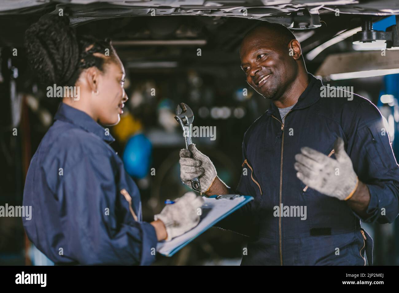 Auto garage worker Black African working together to fix under car ...