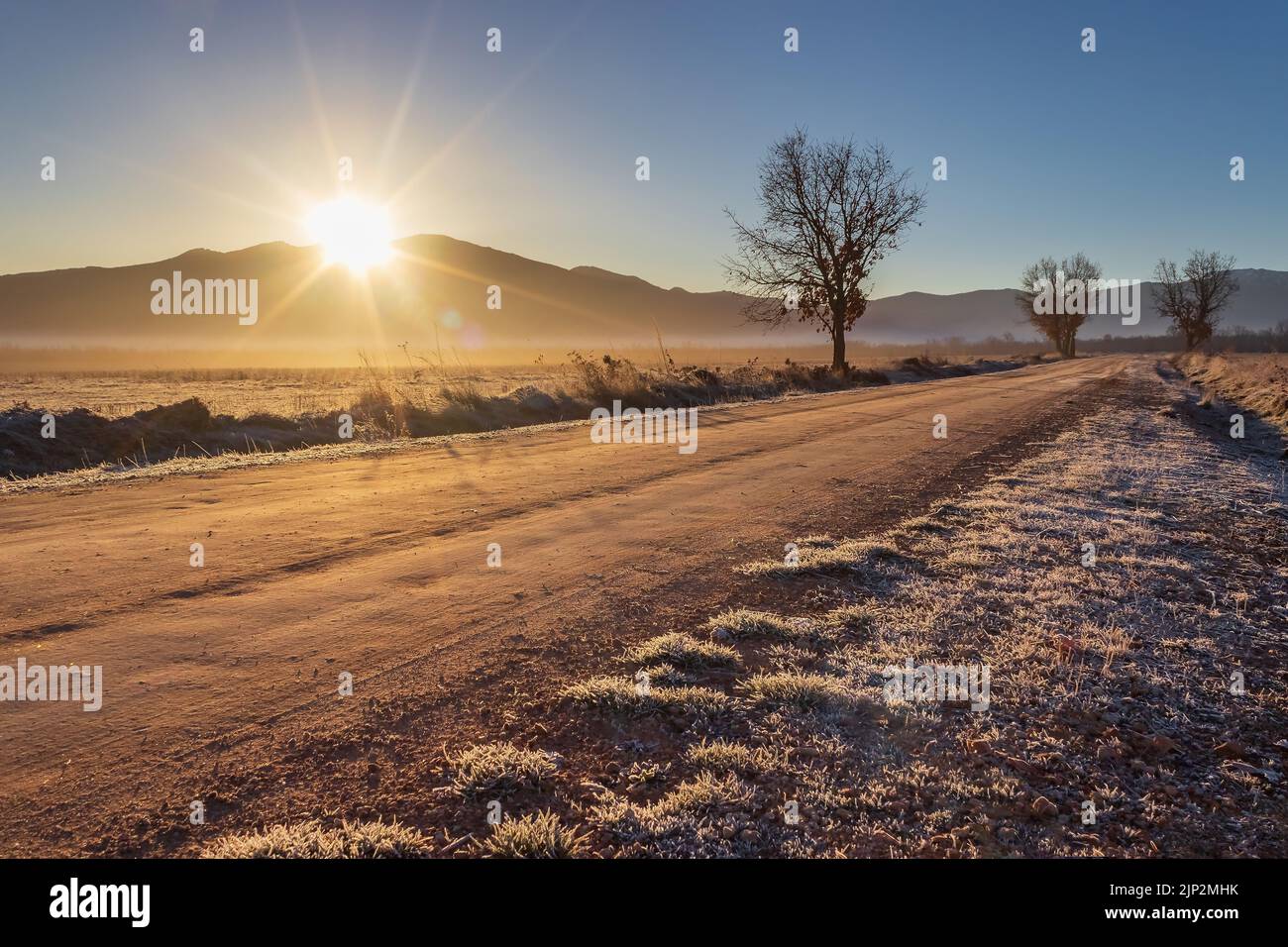 Winter landscape at sunrise with the sun rising between the mountains ...