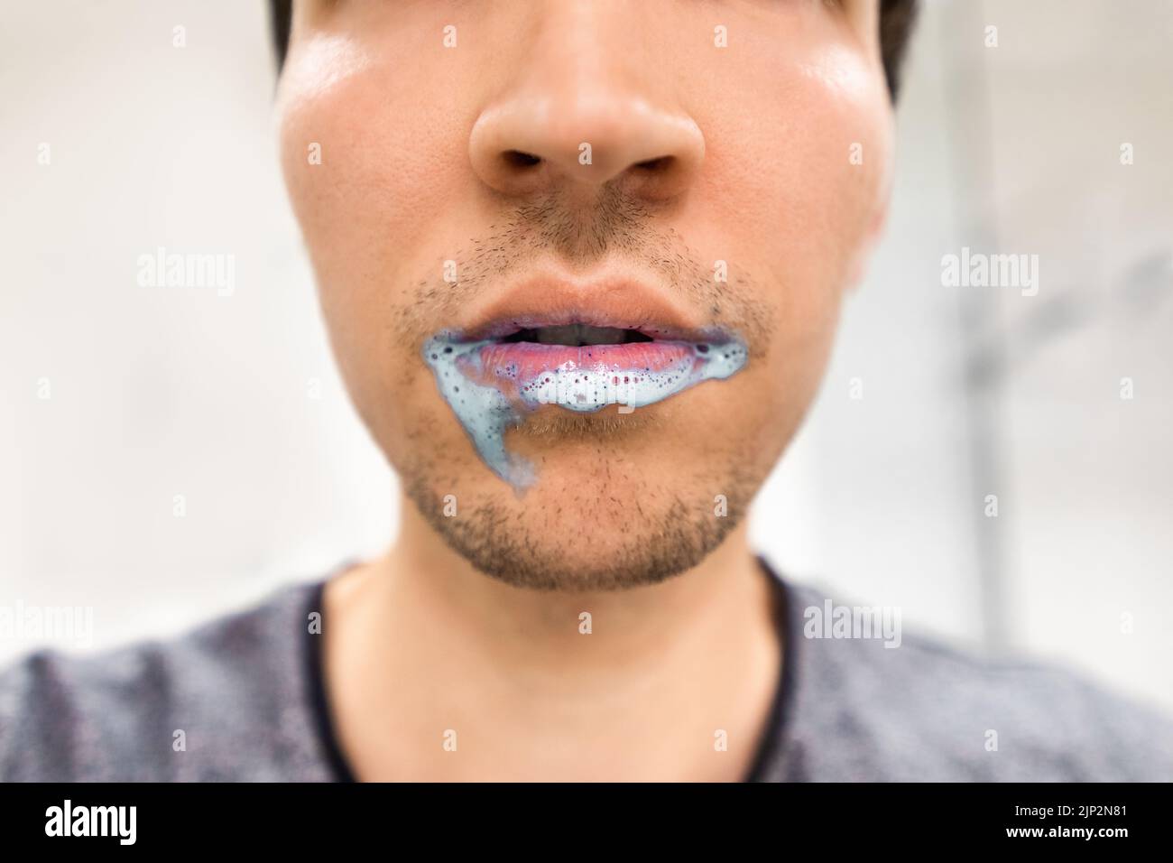 A close up of face of young man. After brushing his teeth the foam of ...