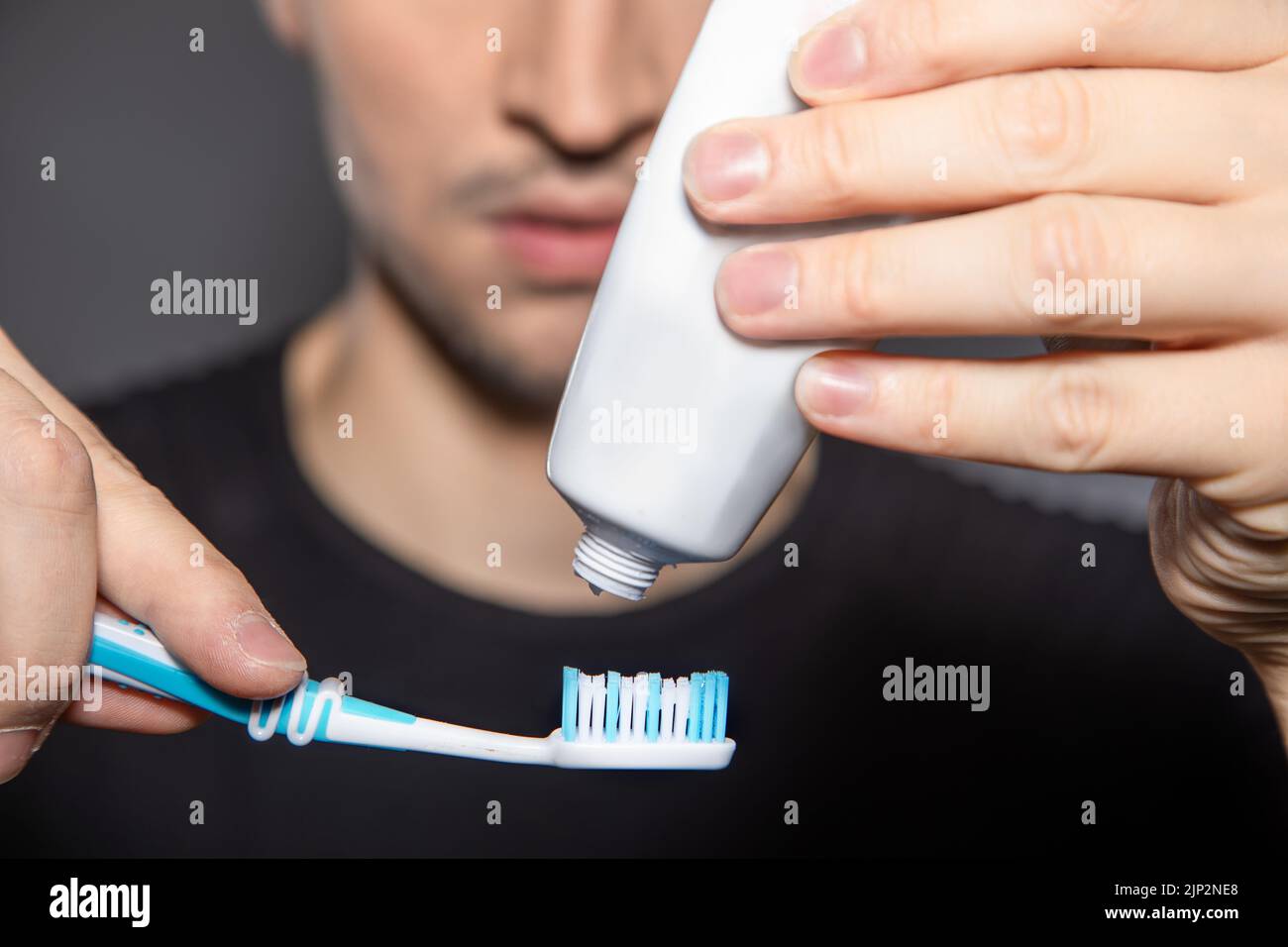 Closeup of young man hold tube of toothpaste and toothbrush and is ...