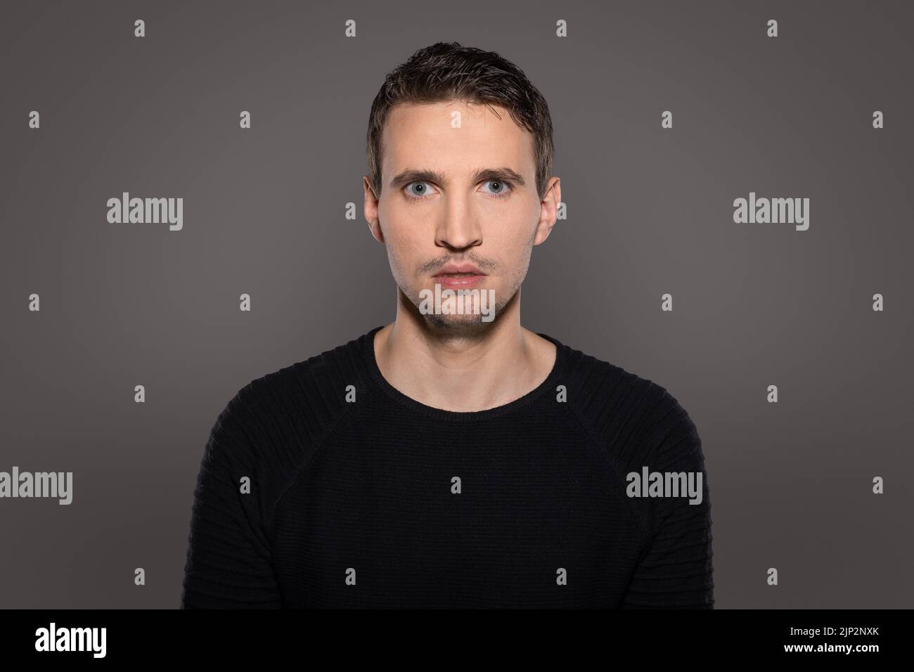 A closeup of young man with horrified expression stand isolated on grey ...