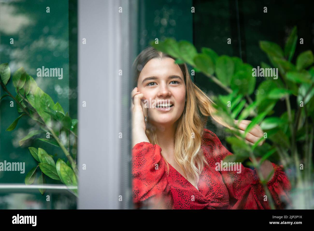 A girl talking on the phone, view from the street through the window ...