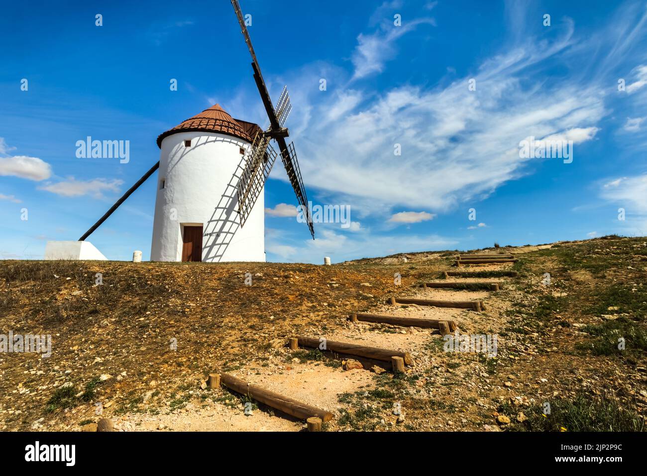 Old white windmills, made of stone, on the field with blue sky and ...