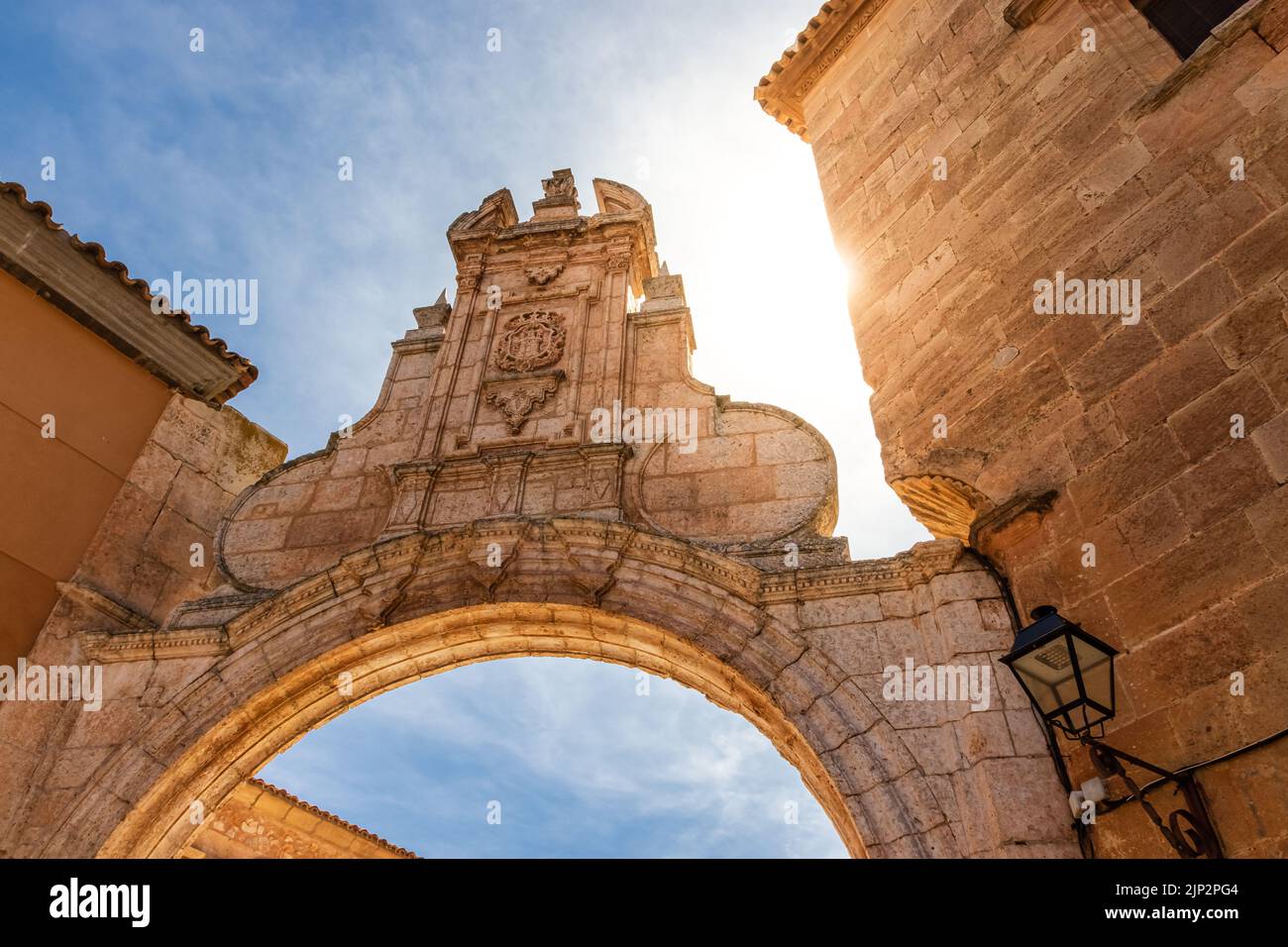 Arch of old stone building with sun glare on blue sky. La Mancha Spain ...