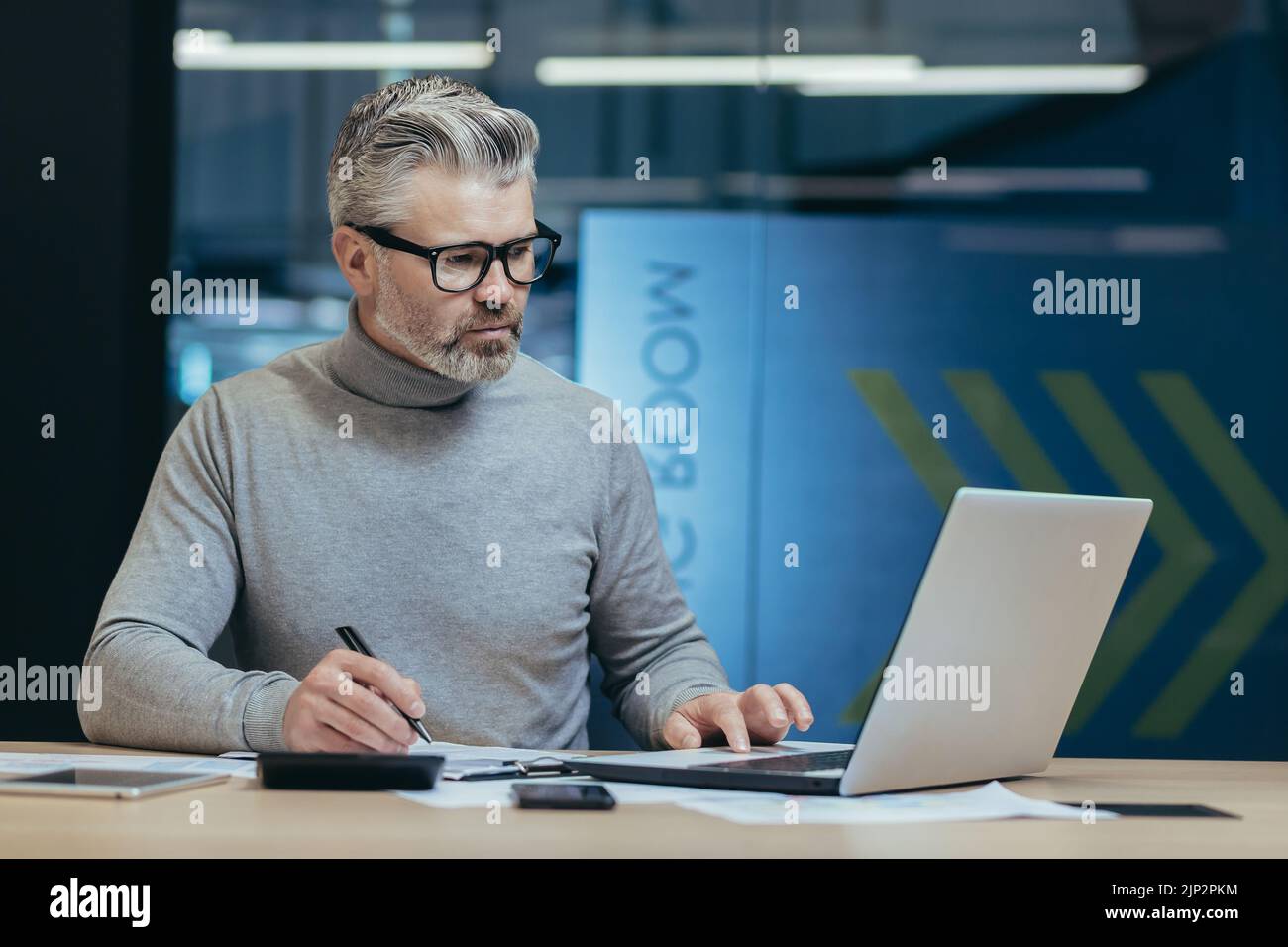 serious businessman behind paper work in office, gray-haired investor ...