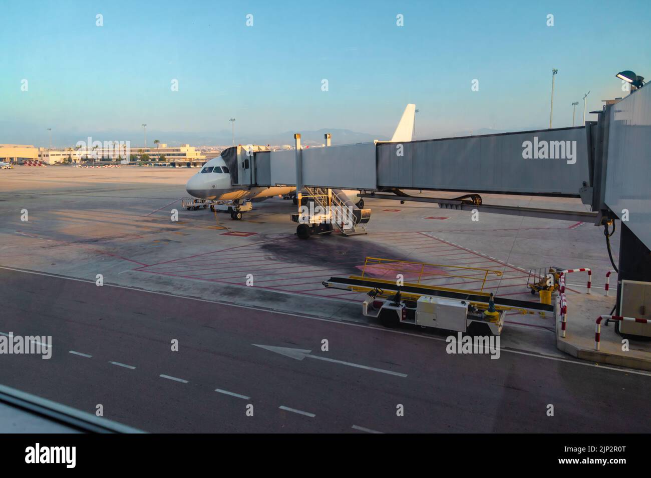 Airplane standing on ground with docked passenger bridge for passing ...