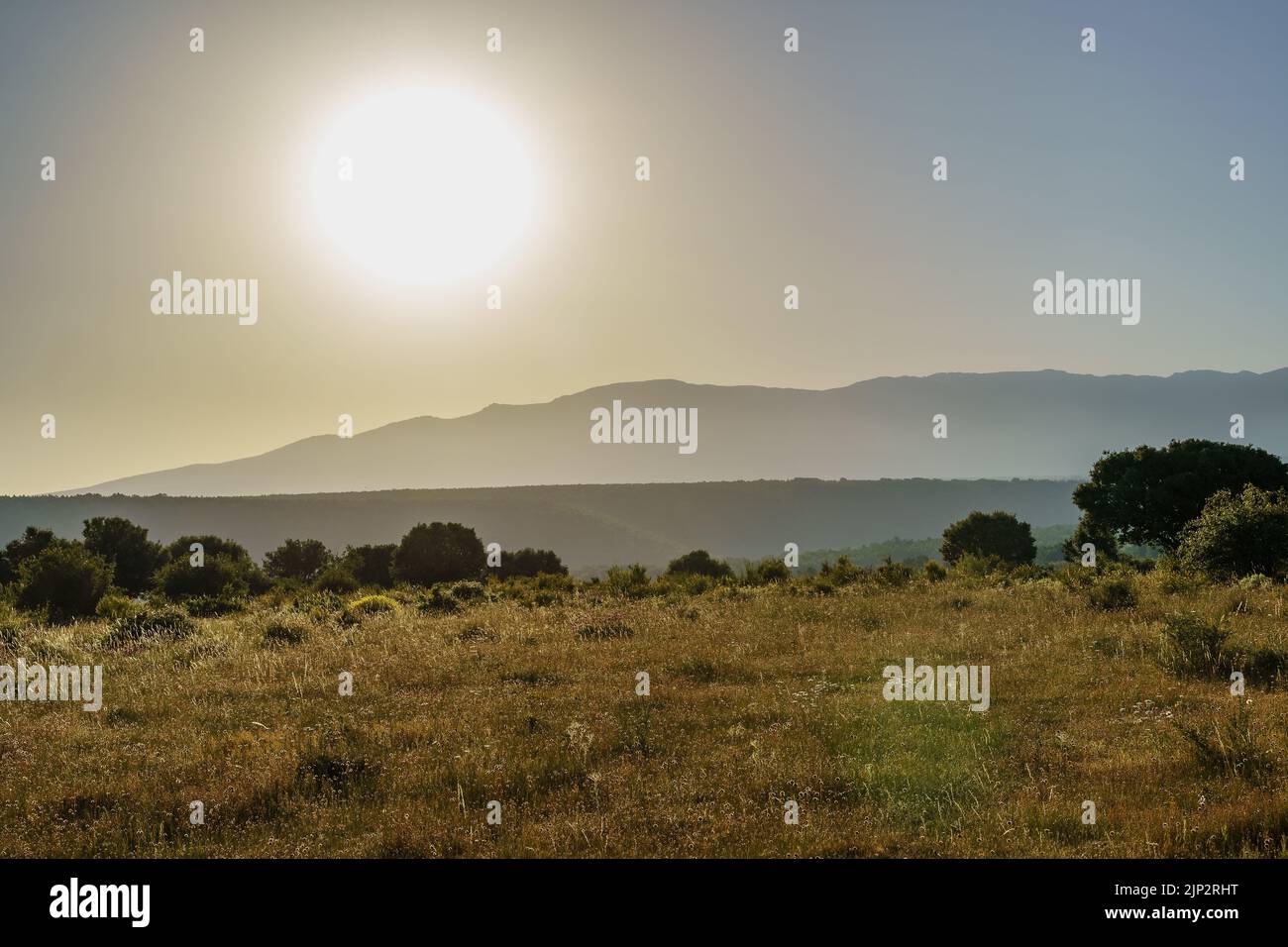 Mountain landscape at sunrise with big sun rising over the horizon ...