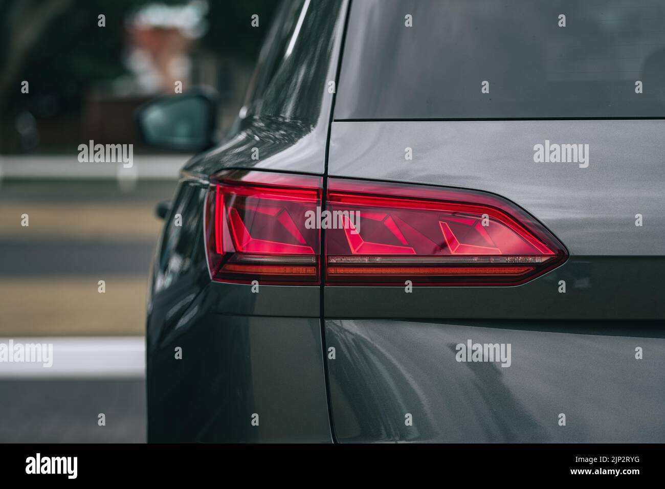 A closeup of a red taillight of a gray car in a parking lot Stock Photo ...