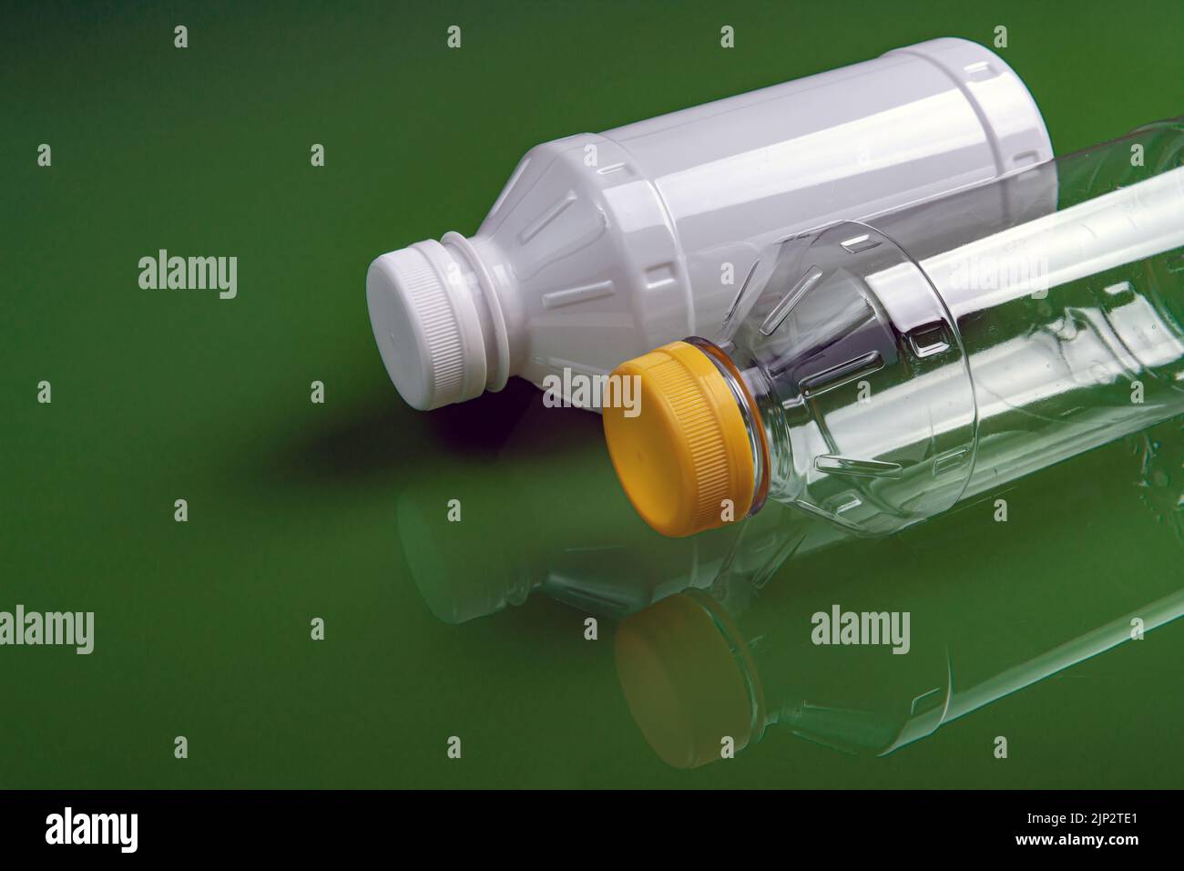 Closeup view of plastic bottles with reflection on a green background ...