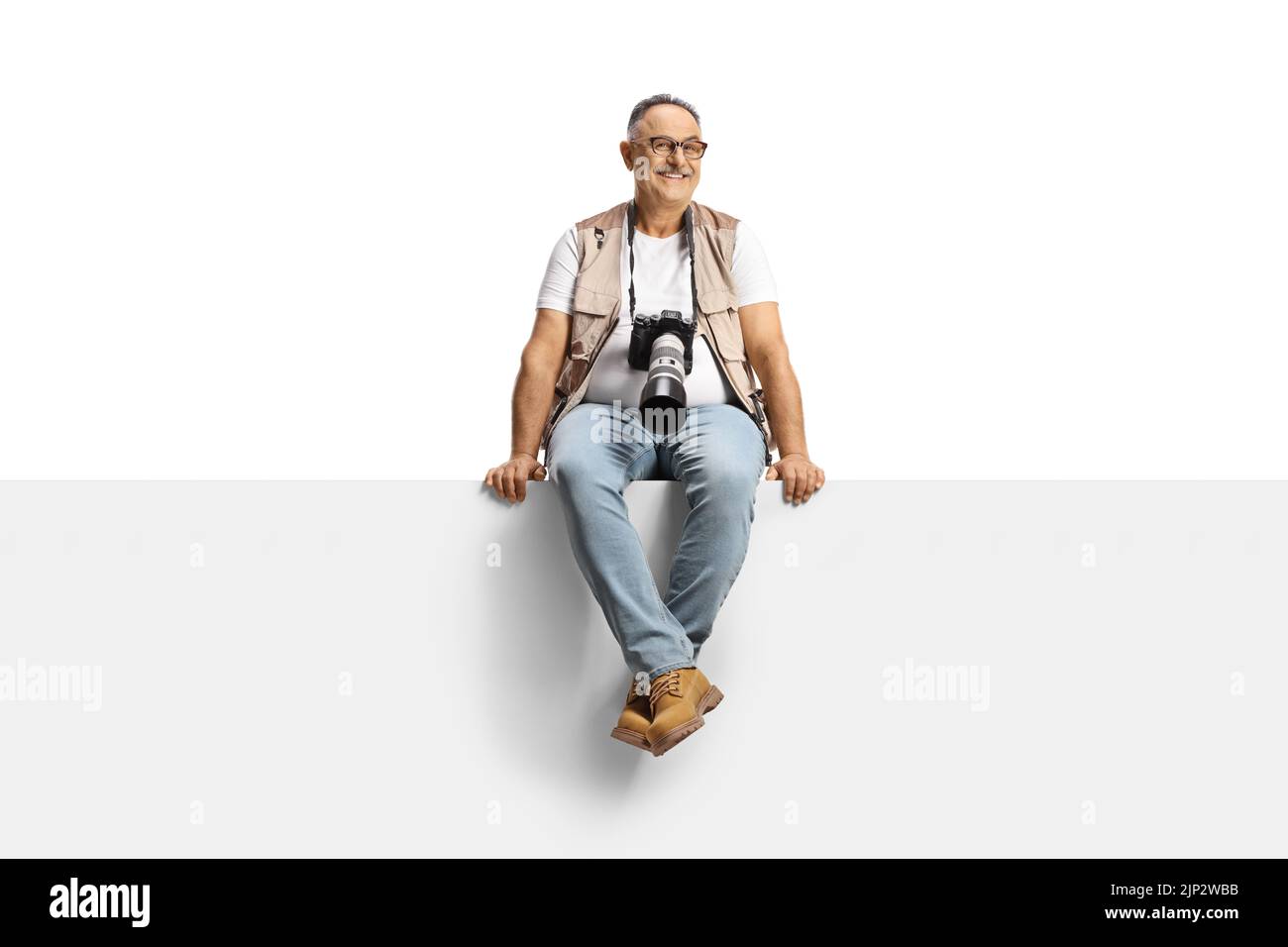 Photographer with a camera sitting on a blank panel and smiling at ...