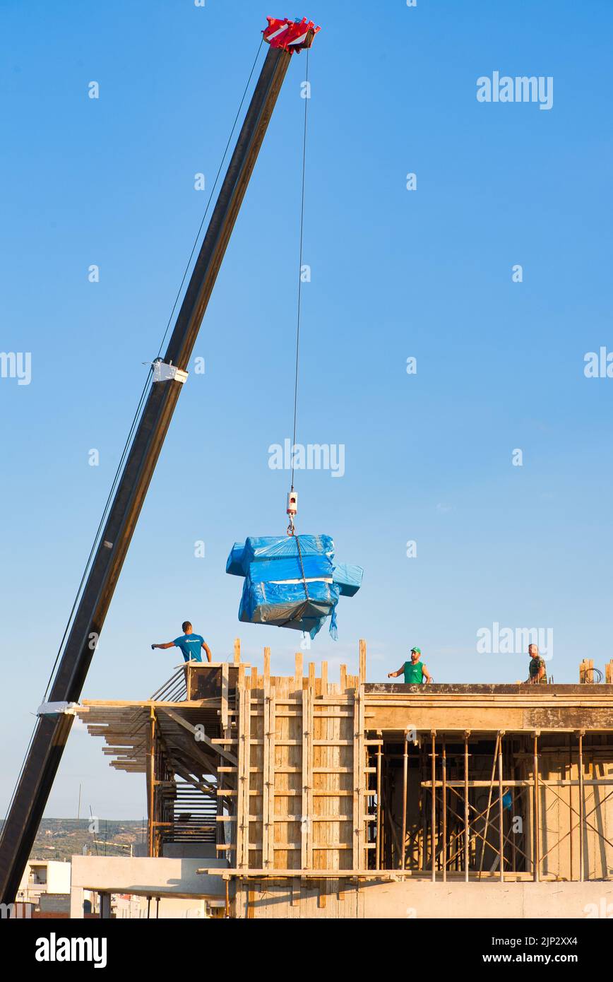 construction workers unload building materials from a crane Stock Photo ...