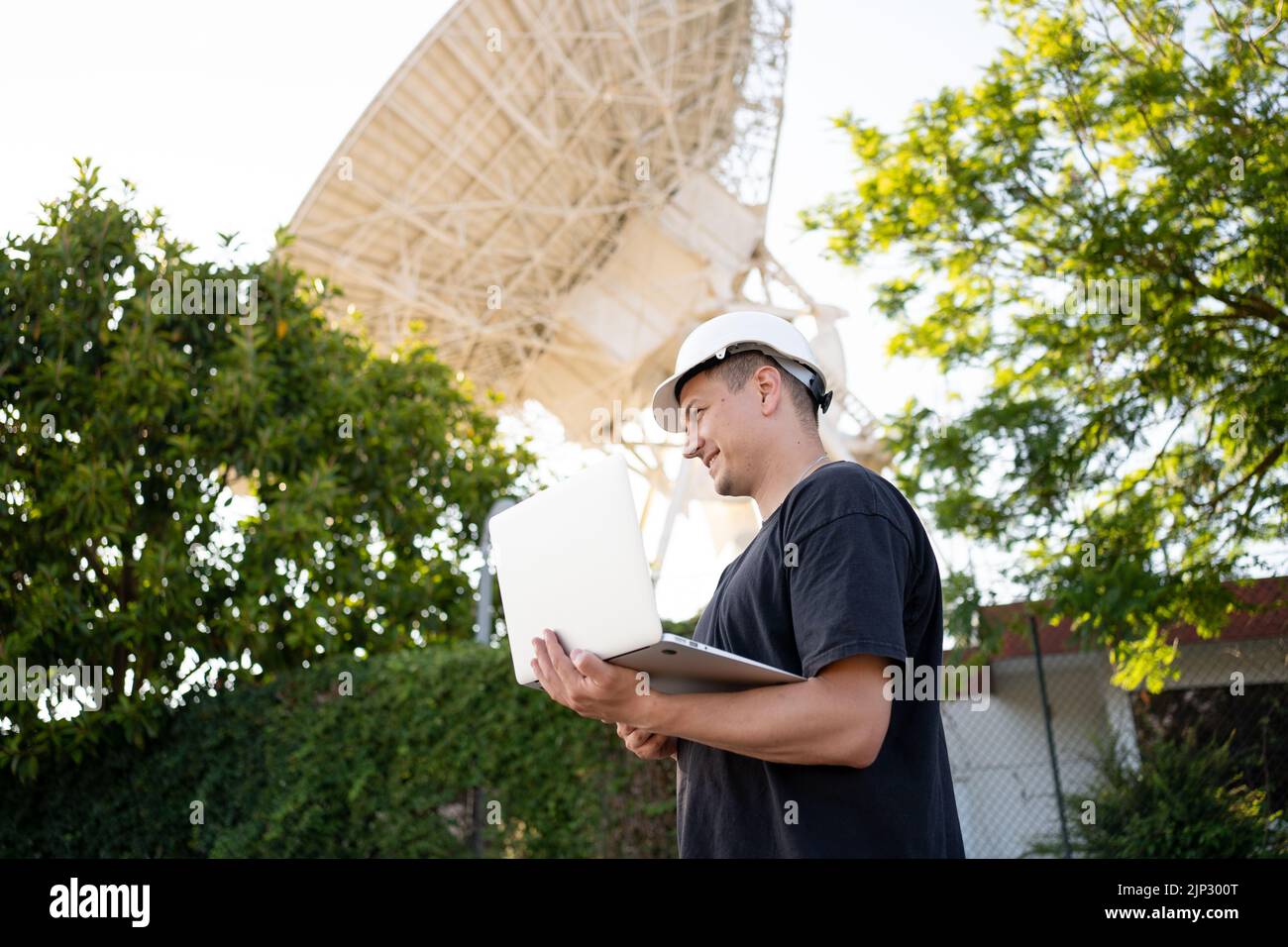 Engineer testing earth based astronomical radio telescope use laptop ...