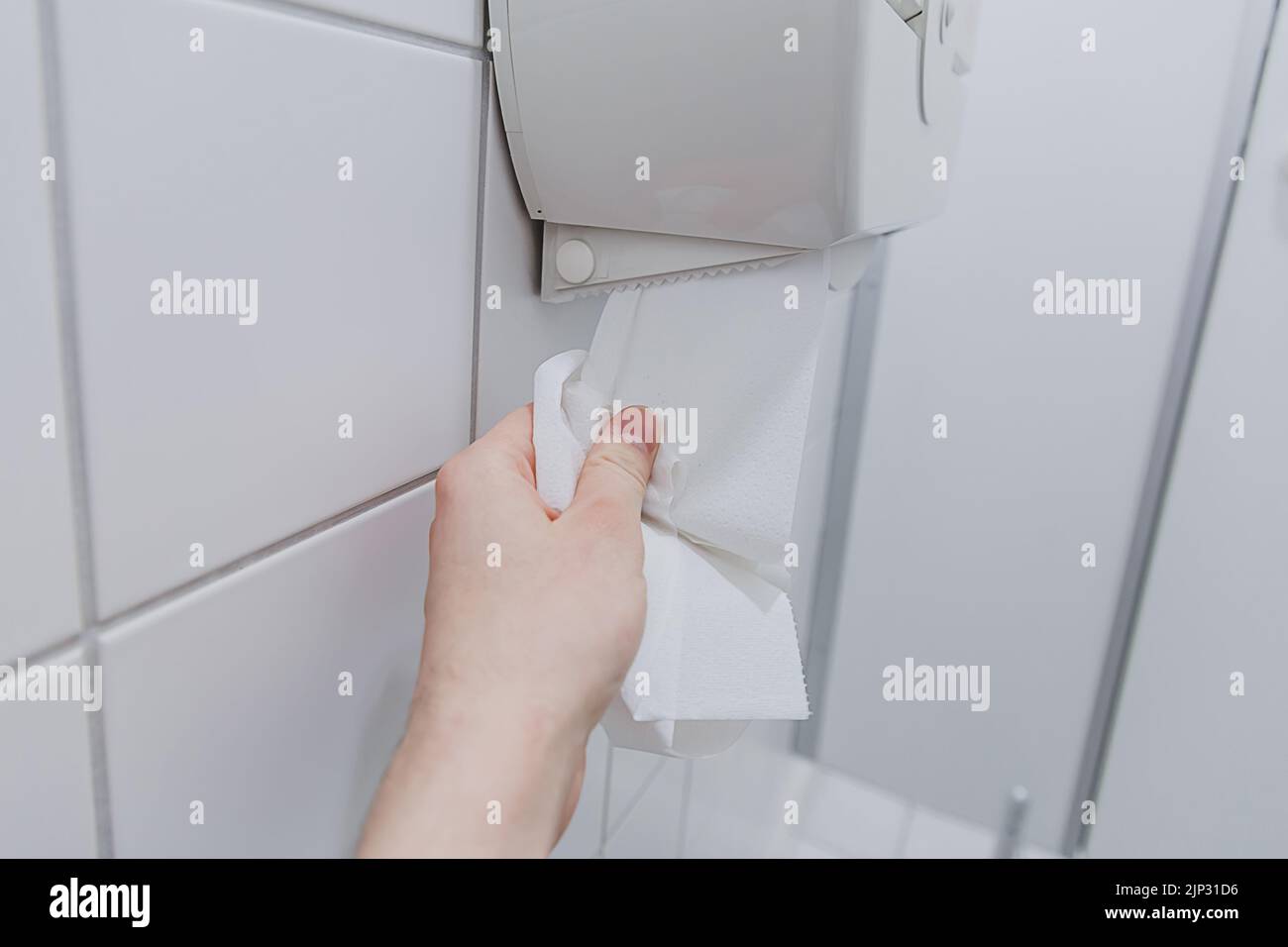 A person pulling a sheet of toilet paper in a public restroom Stock ...