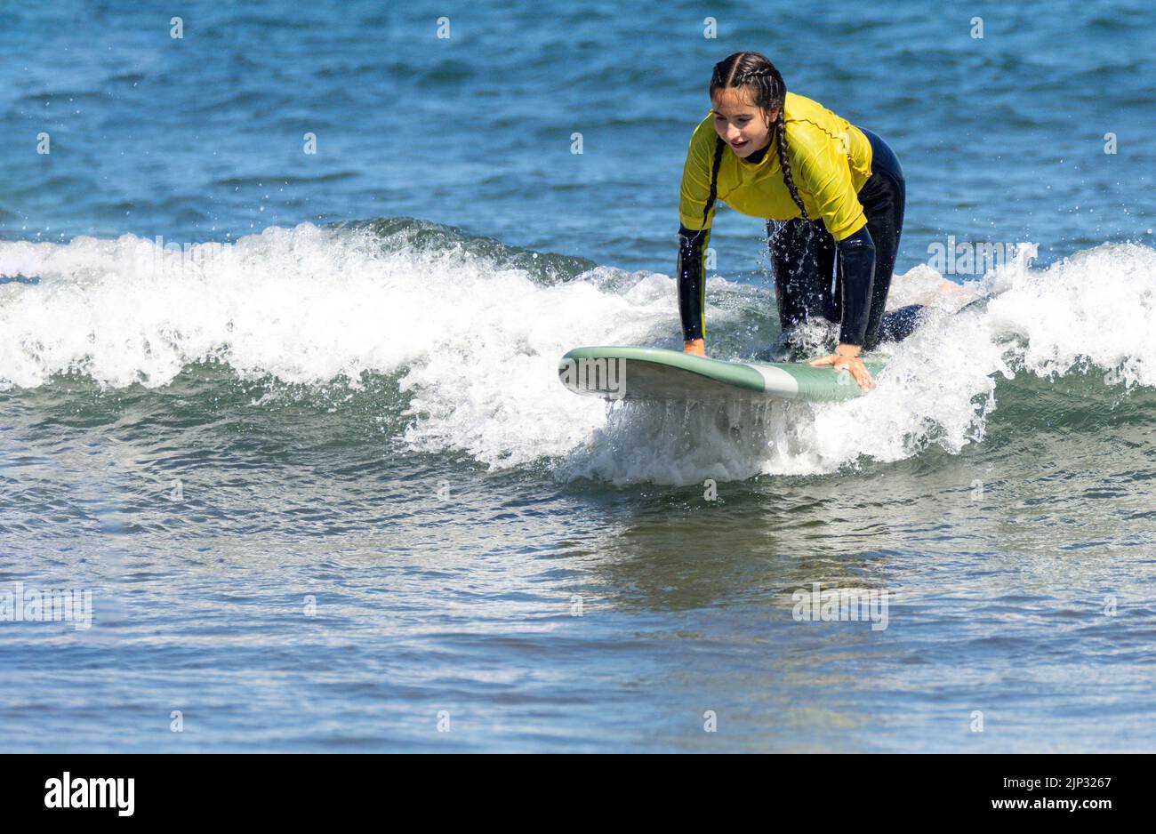 Woman surfing while kneeling on a surfboard Stock Photo - Alamy