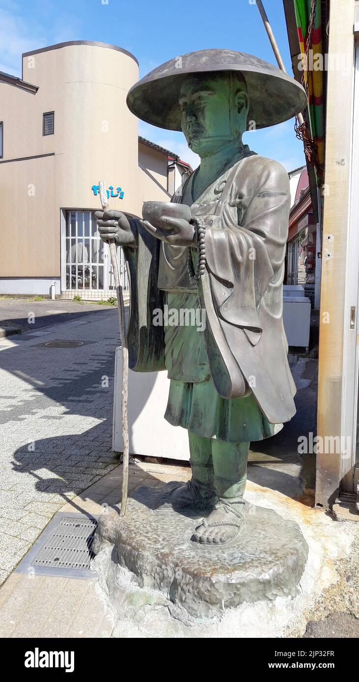 A vertical shot of the statue of Monk Tojinbo on the sidewalk in Japan ...