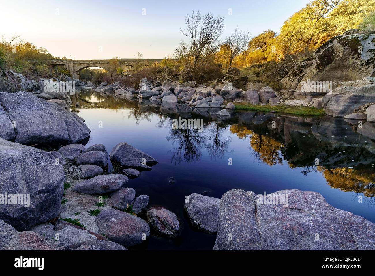 Winter landscape with river, reflections in the water and large rocks ...