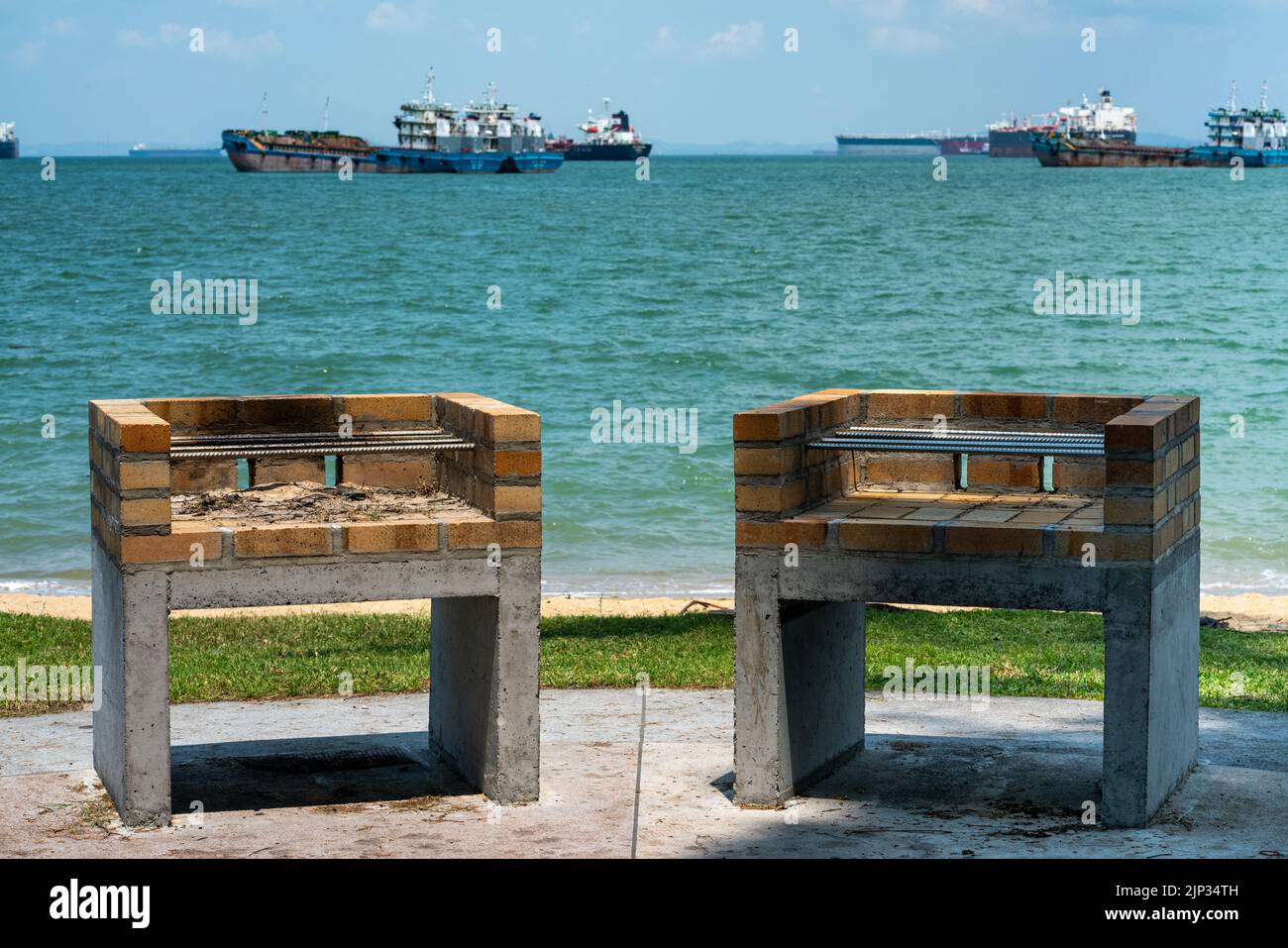 Two barbecue pits at tropical East Coast Beach in Singapore. Ships on ...