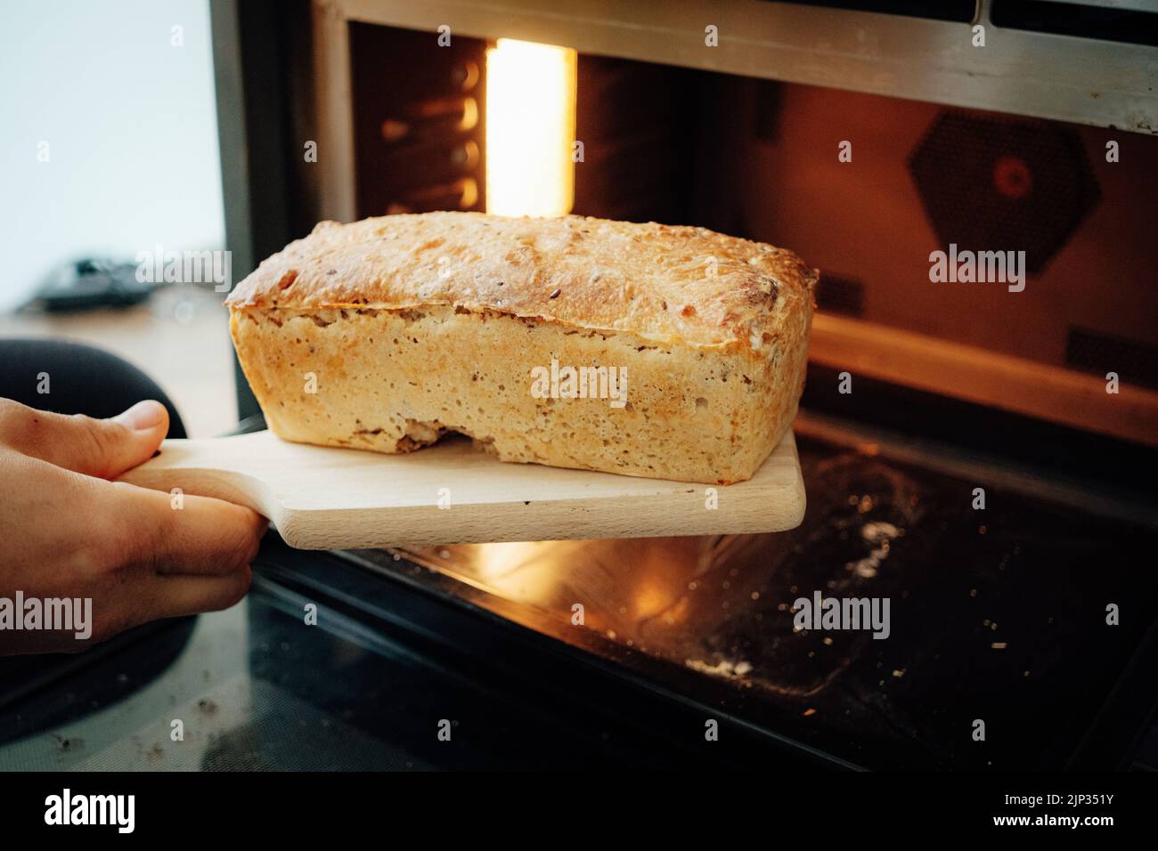 A closeup of a person's hands taking fresh baked bread out of the oven ...