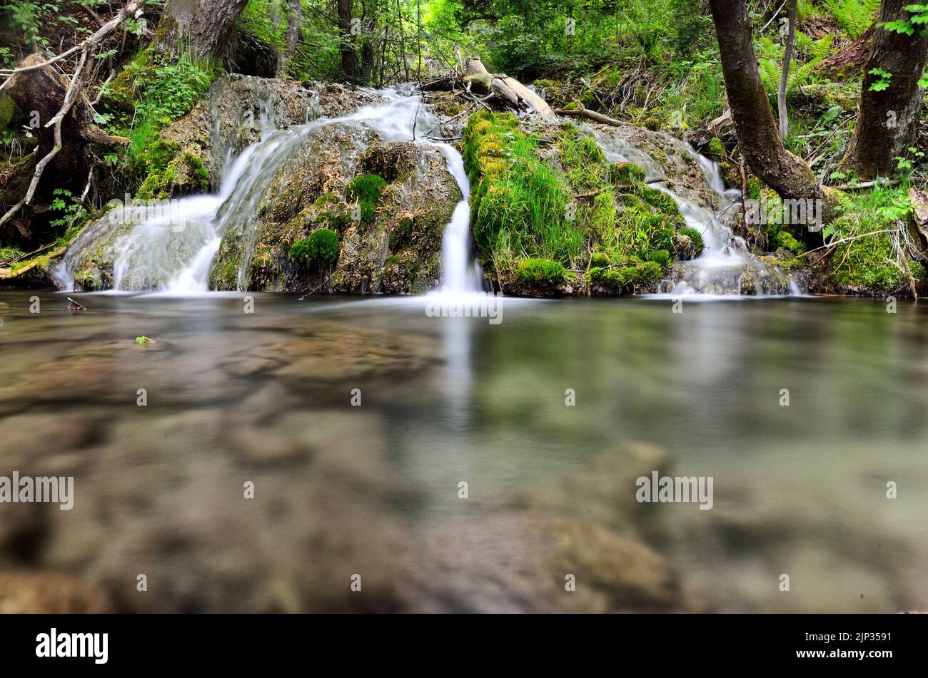 A scenic view of a small waterfall flowing over rocks covered with moss ...