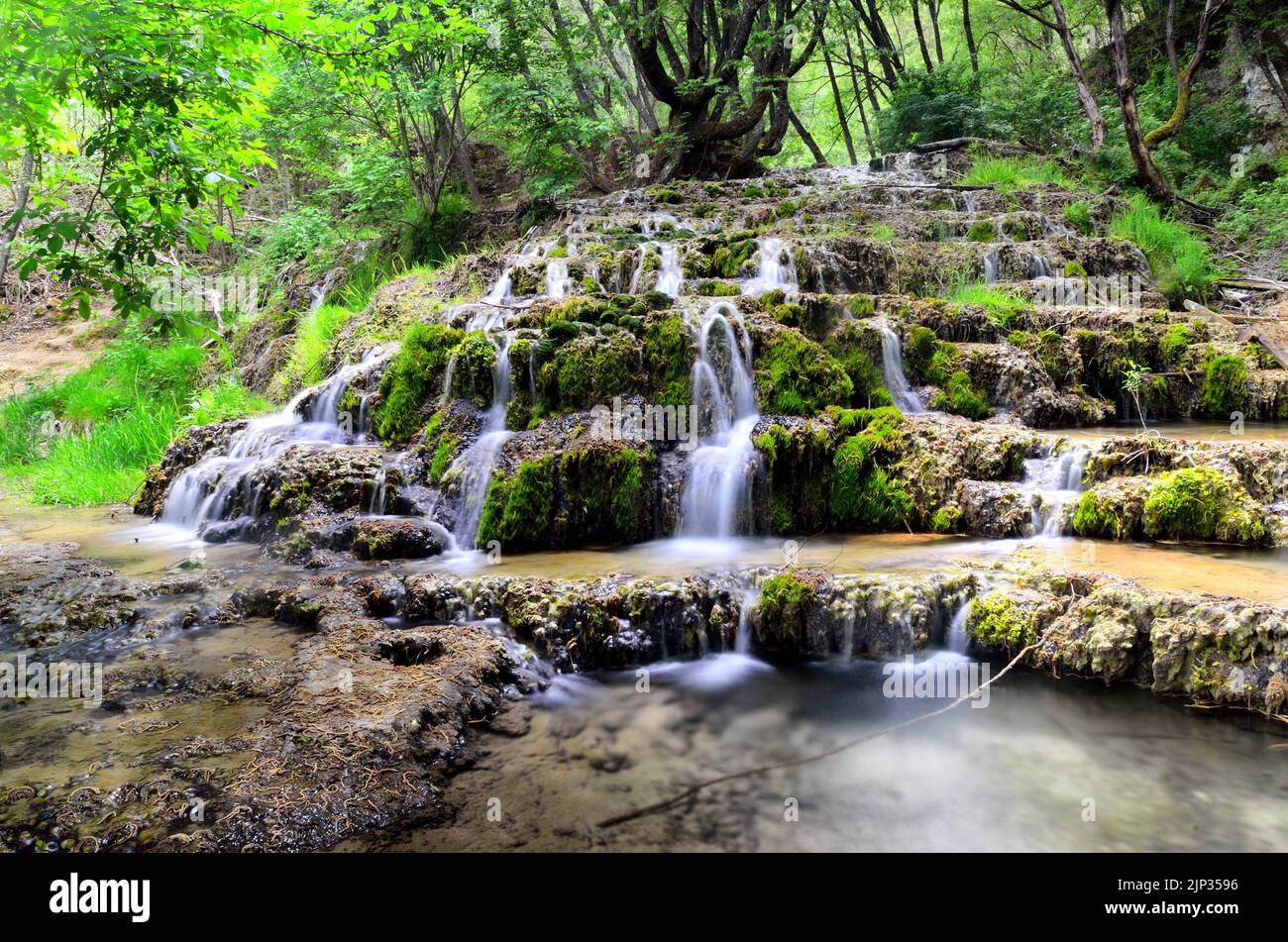 A landscape view of a waterfall flowing over rocks covered with moss ...