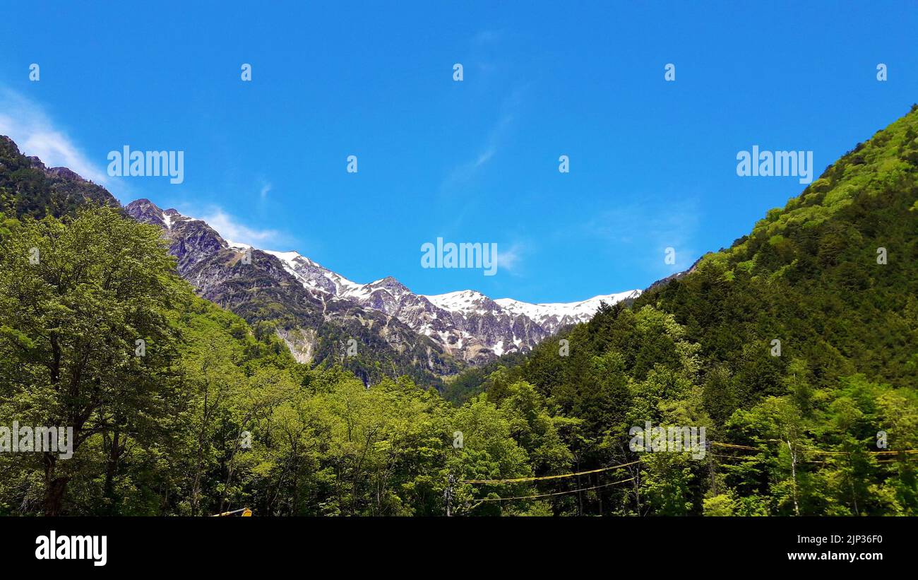 A beautiful landscape of green trees and mountains of Kamikochi resort ...