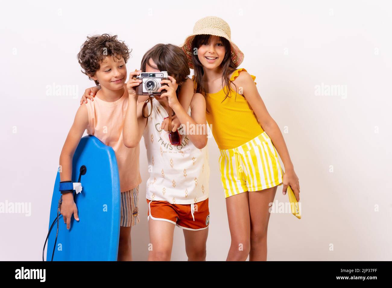 Two cute boys with a girl posing happily in summer outfits Stock Photo ...